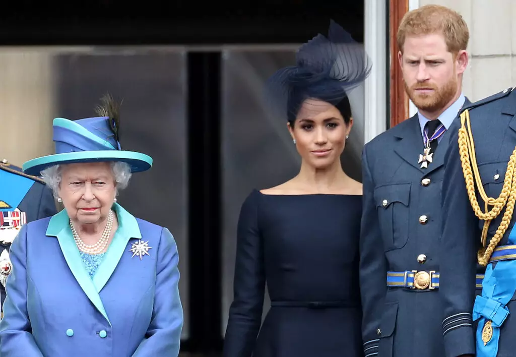 Elísabet drottning í bláum búningi með Harry Bretaprins og Meghan Markle á svölum