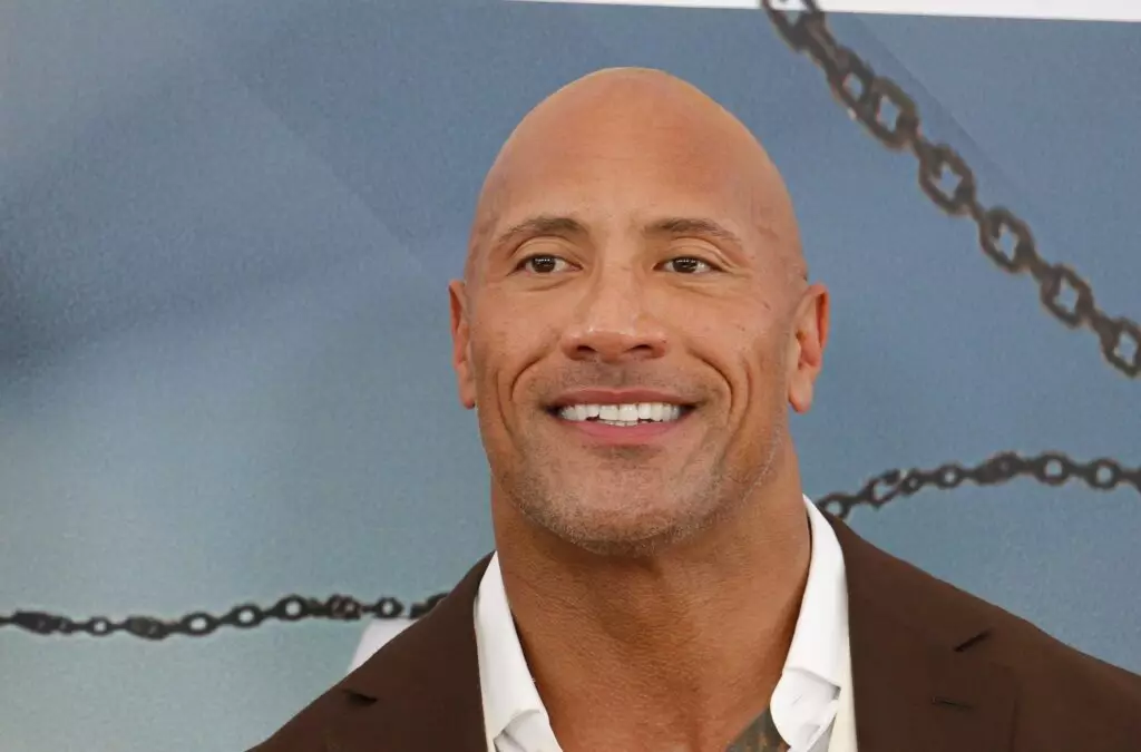 Dwayne Johnson na světové premiéře 'Fast & Furious Presents: Hobbs & Shaw' v hnědém obleku a bílé košili.