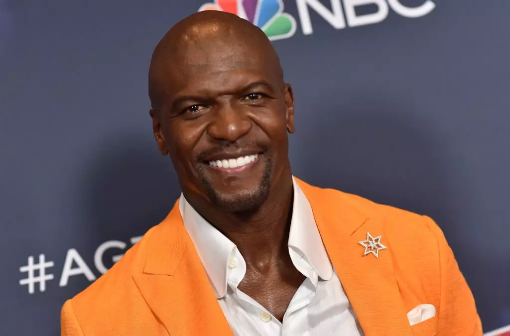 Terry Crews 'America's Got Talent' کے سیمی فائنل میں ایک روشن نارنجی سوٹ، سفید قمیض کے ساتھ پہلے چند بٹنوں کو ختم کر کے، اور اس کے لیپل پر 6 پوائنٹ والا ستارہ پن۔