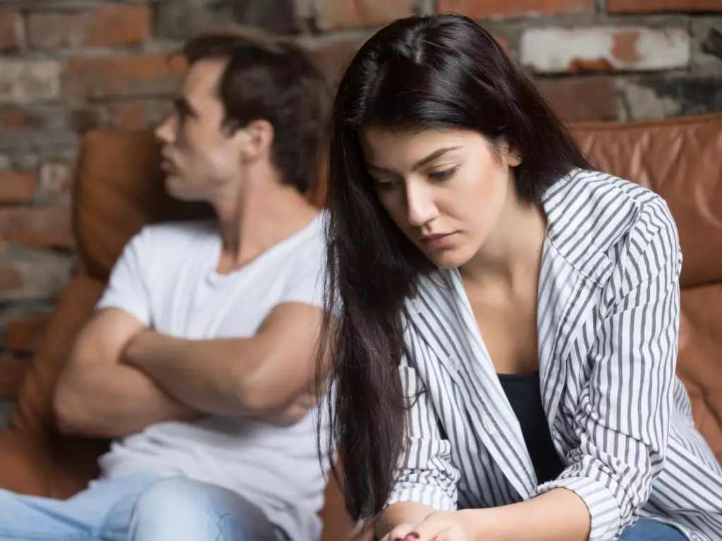 Triste jeune fille pensive pensant à des problèmes de relations assis sur un canapé avec un petit ami offensé, des conflits dans le mariage, un couple bouleversé après une dispute de combat, prenant la décision de rompre et de divorcer