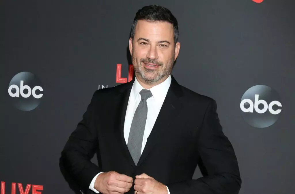 Jimmy Kimmel indossa un abito nero con le mani sullo stomaco.