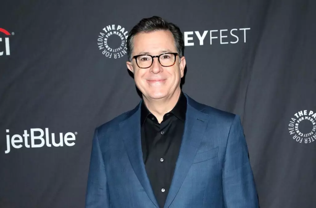 Stephen Colbert smiler og har på seg en blå dress.