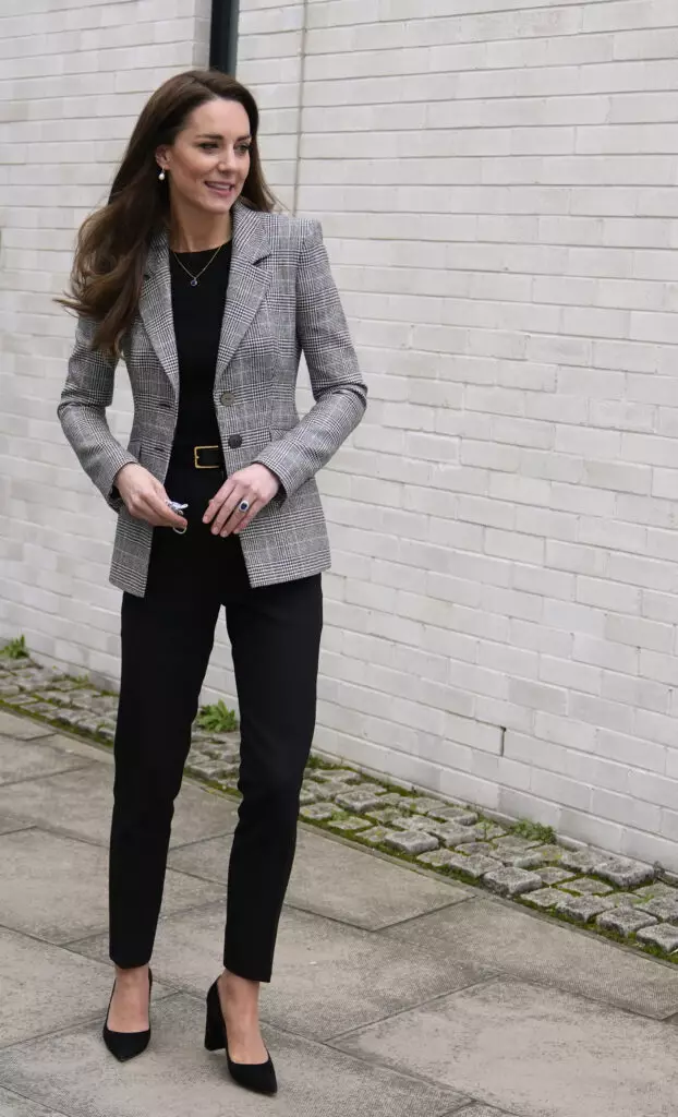 Kate Middleton i sorte slacks, sort bælte, sort top og grå tweedjakke og sorte hæle