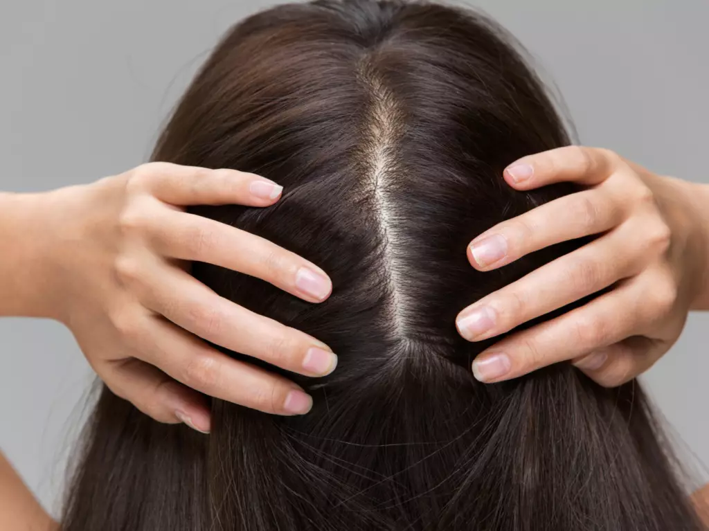 een vrouw die haar hoofdhuid masseert