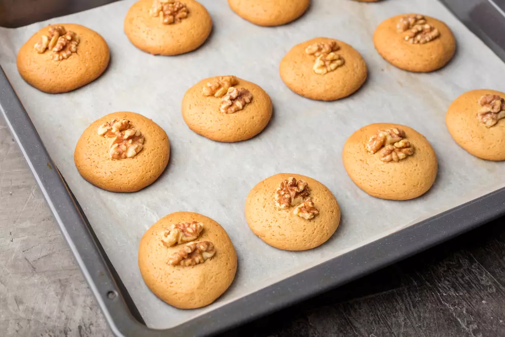 Kue pecan panggang mendingin di atas loyang yang dilapisi kertas roti.