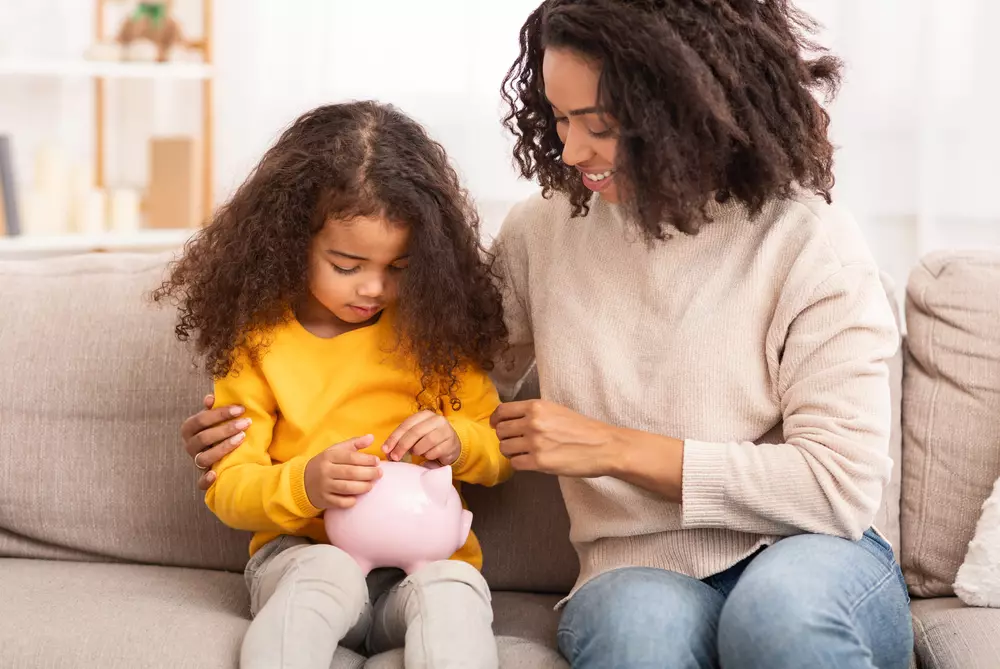 Une mère avec sa fille, qui tient une tirelire.