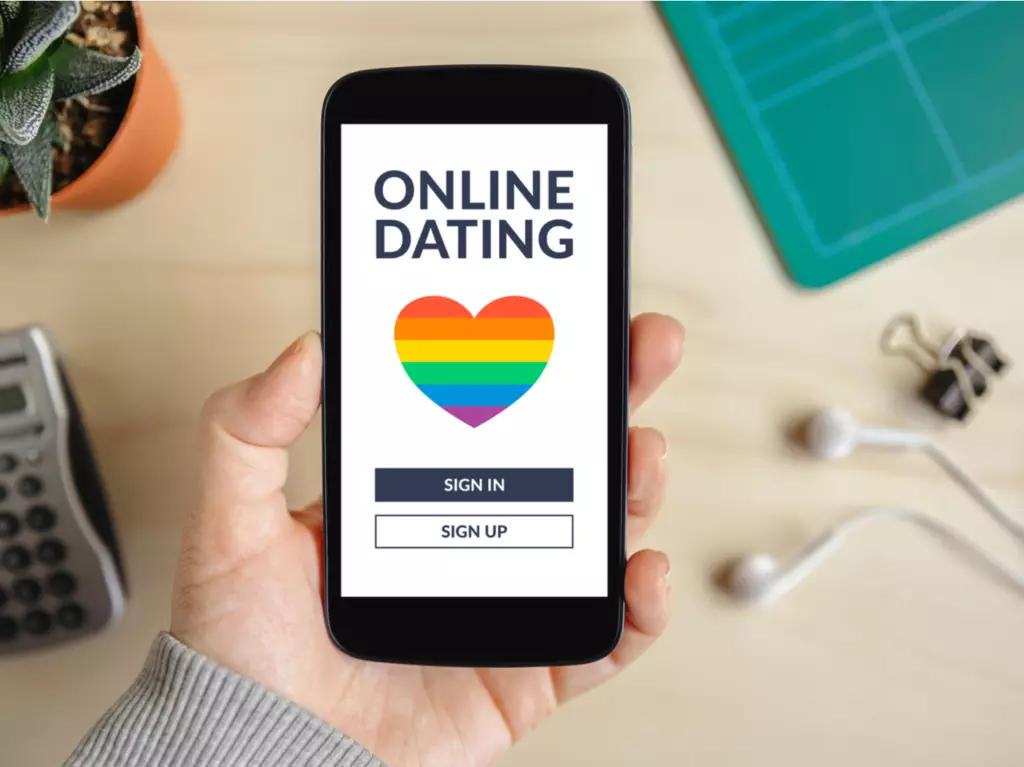 Hand, die Smartphone mit LGBT-Dating-App-Konzept auf dem Bildschirm hält. Homosexuelles Online-Dating. Ansicht von oben