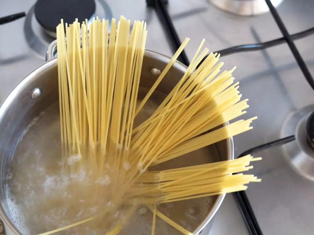 Spaghetti koken in een zilveren pot met heet water