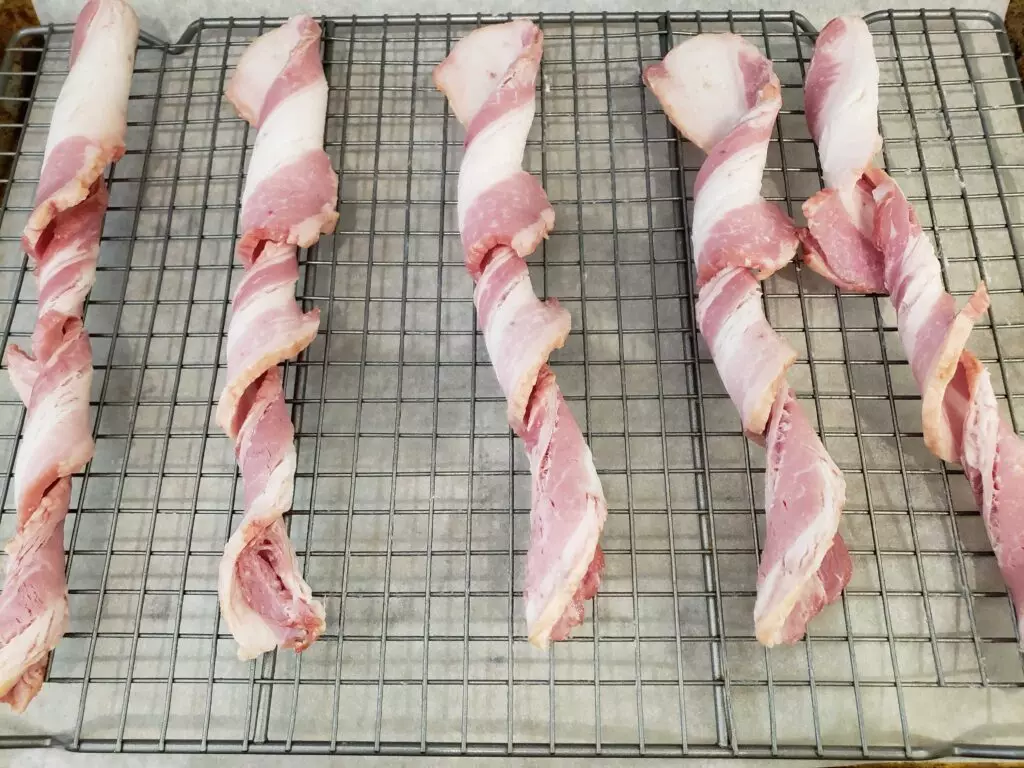 Immagine di pancetta cruda attorcigliata e posizionata lungo la griglia di raffreddamento.