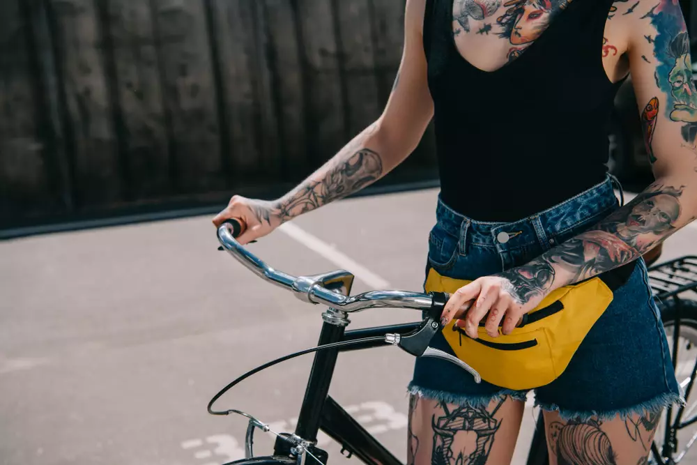 image recadrée d'une élégante fille tatouée debout avec un vélo dans la rue