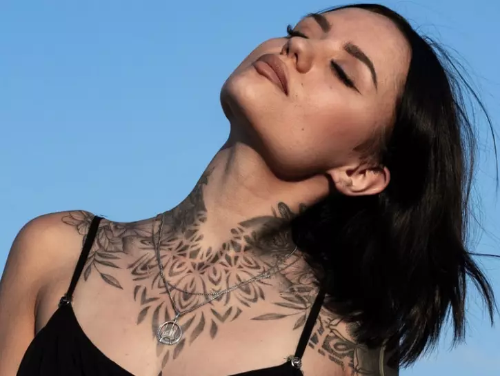 Femme avec un tatouage de points noirs sur le cou et les clavicules